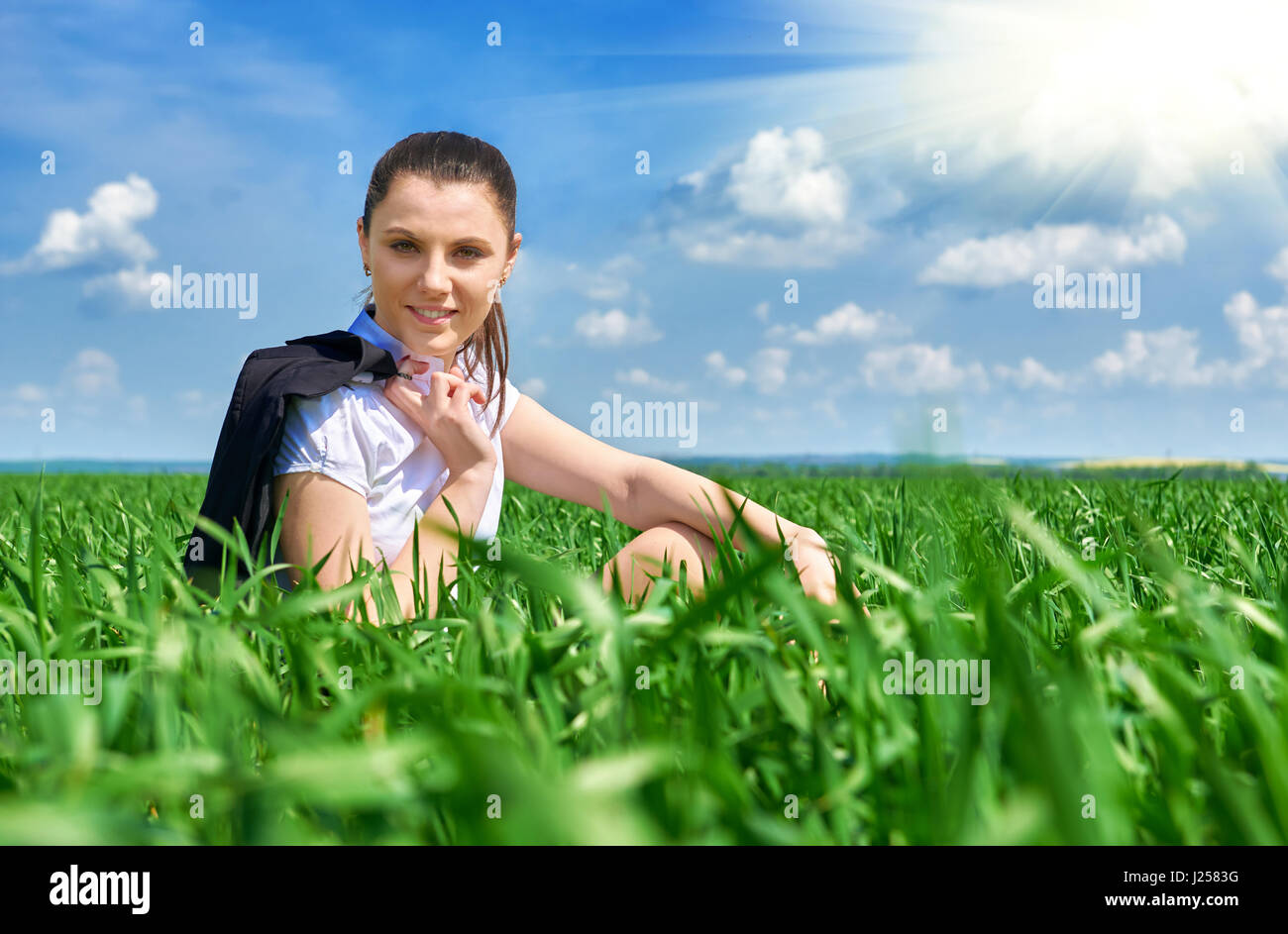 Business woman relaxing in green grass field outdoor under sun ...