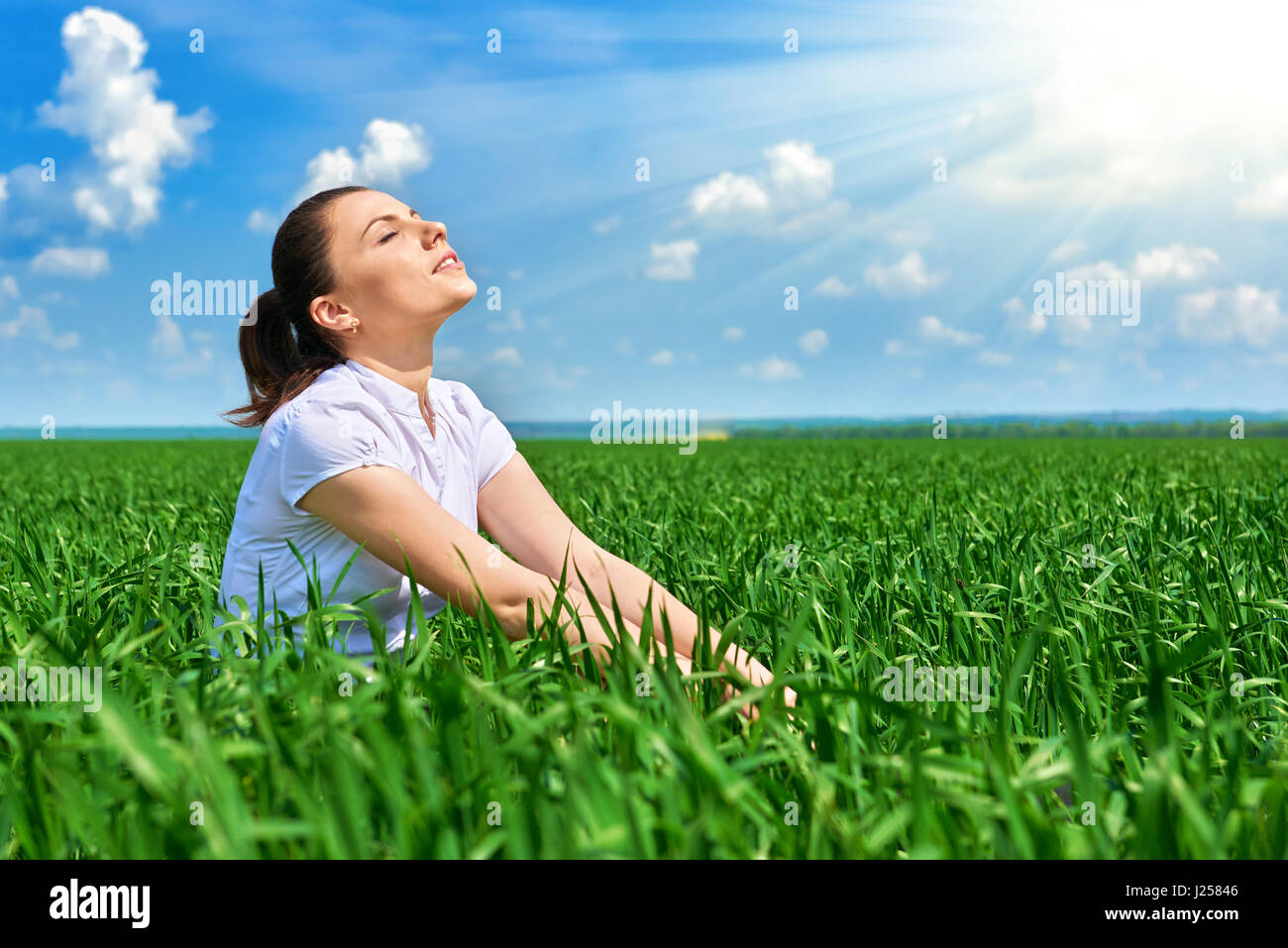Business woman relaxing in green grass field outdoor under sun ...