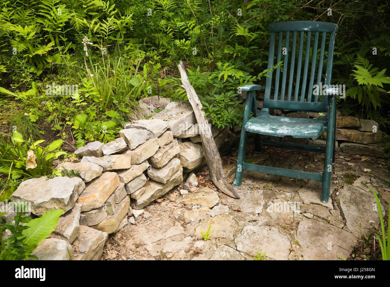 Green plastic chair on a flagstone patio in a landscaped residential ...