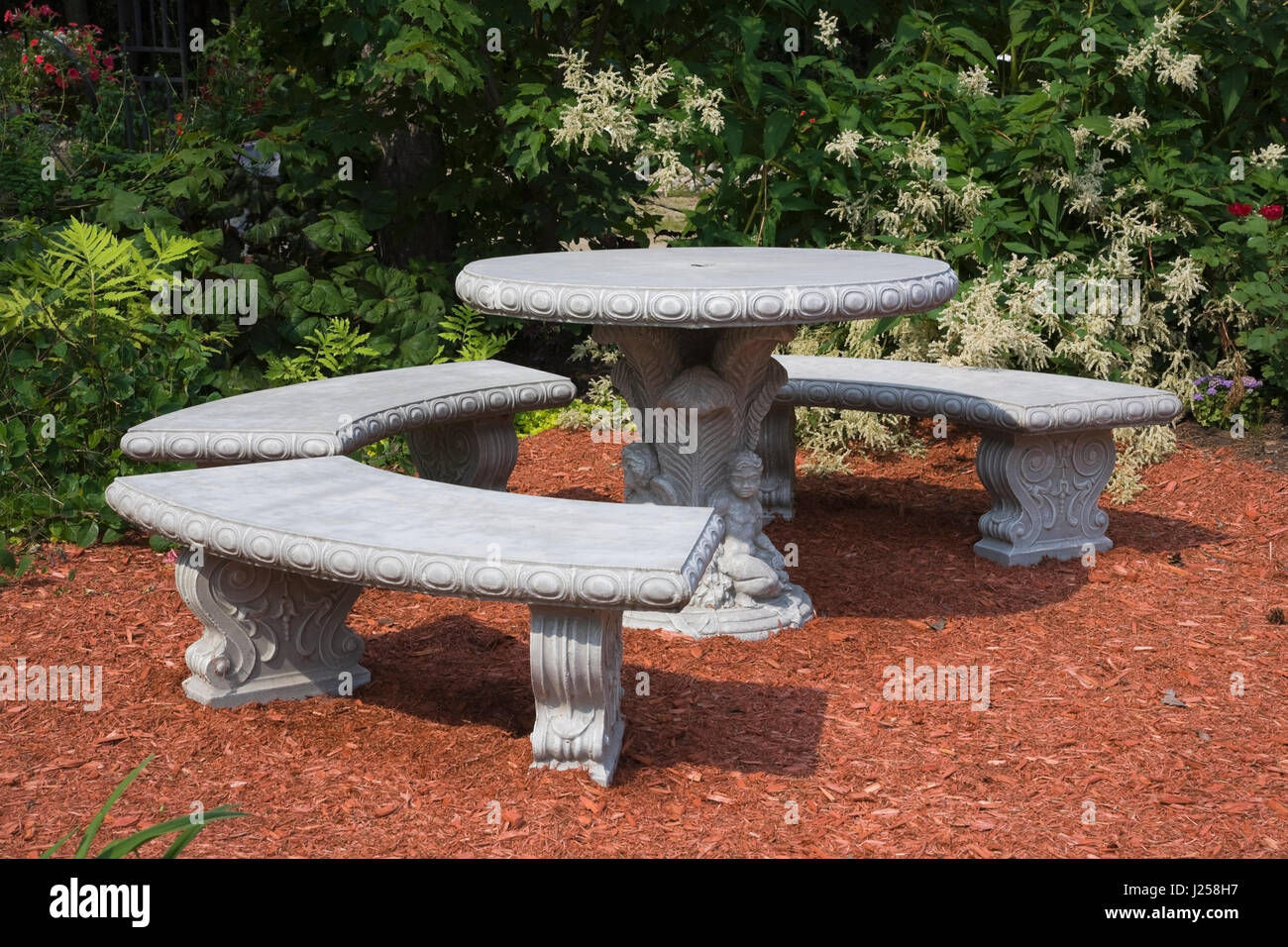 Crescent shaped sitting benches and round table in landscaped backyard ...