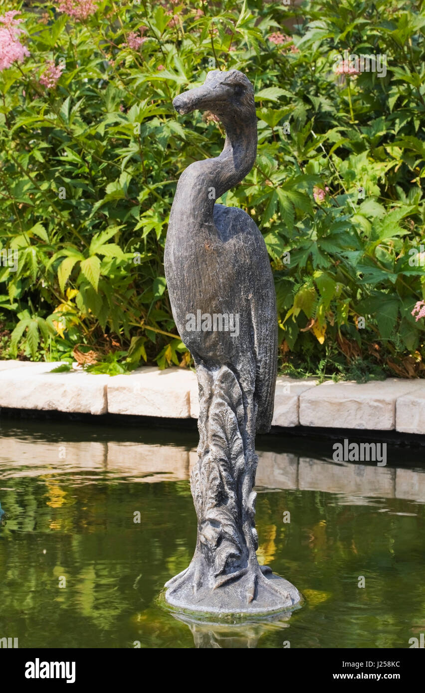 Statue of heron bird in a water fountain basin in a landscaped backyard ...