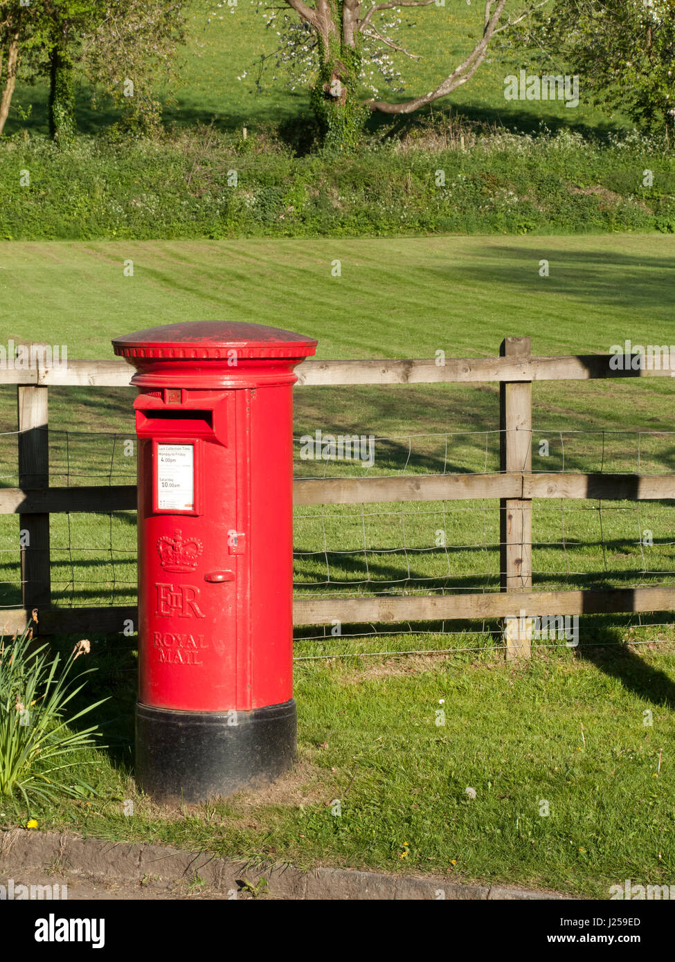 Red Royal Mail postbox in countryside rural setting with village ...