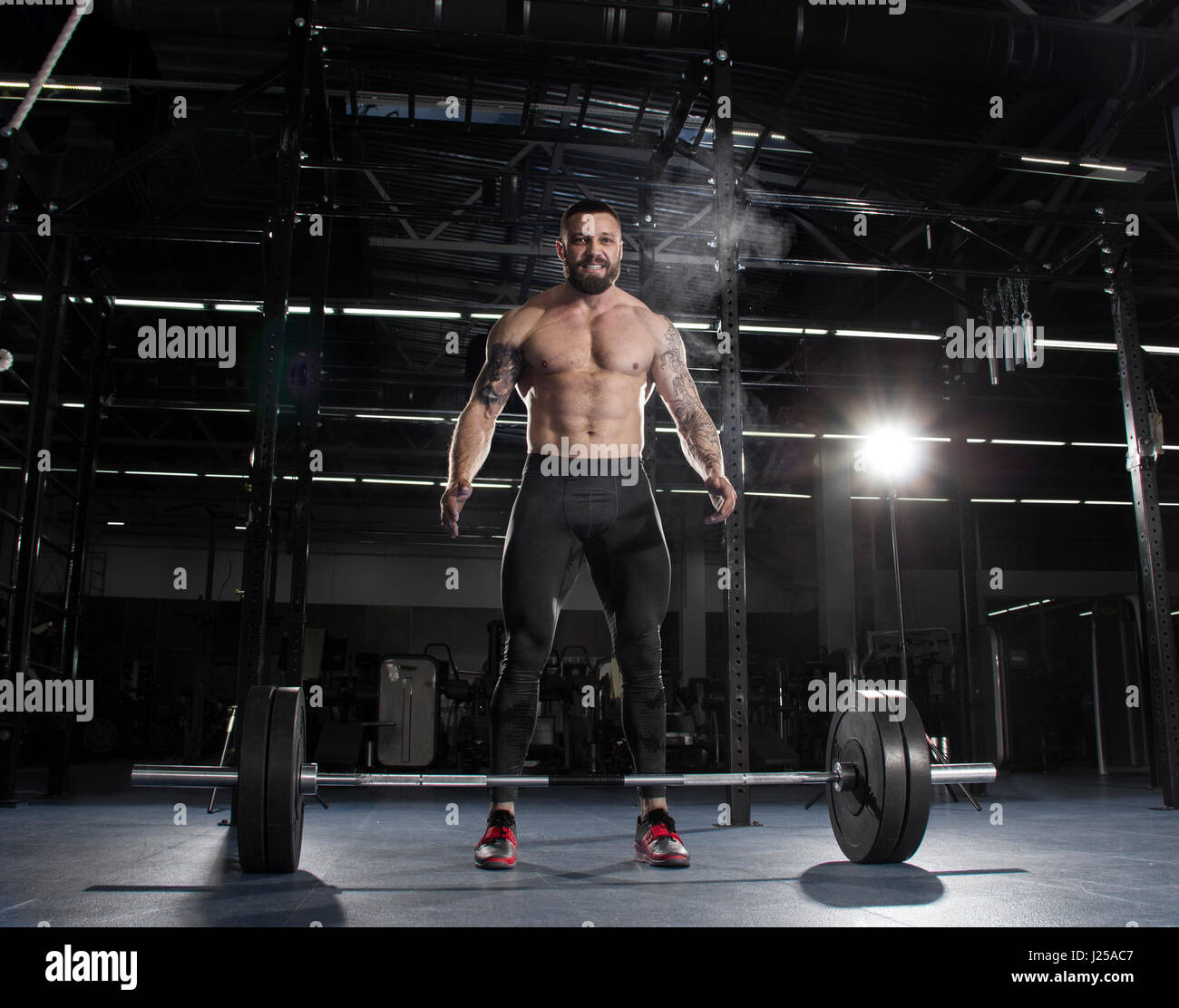 Muscular shirtless bodybuilder clapping hands before the barbell ...