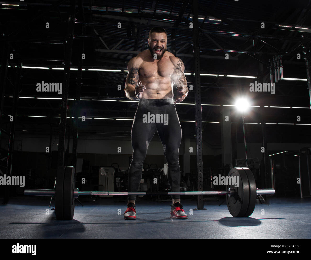 Muscular shirtless bodybuilder clapping hands before the barbell ...