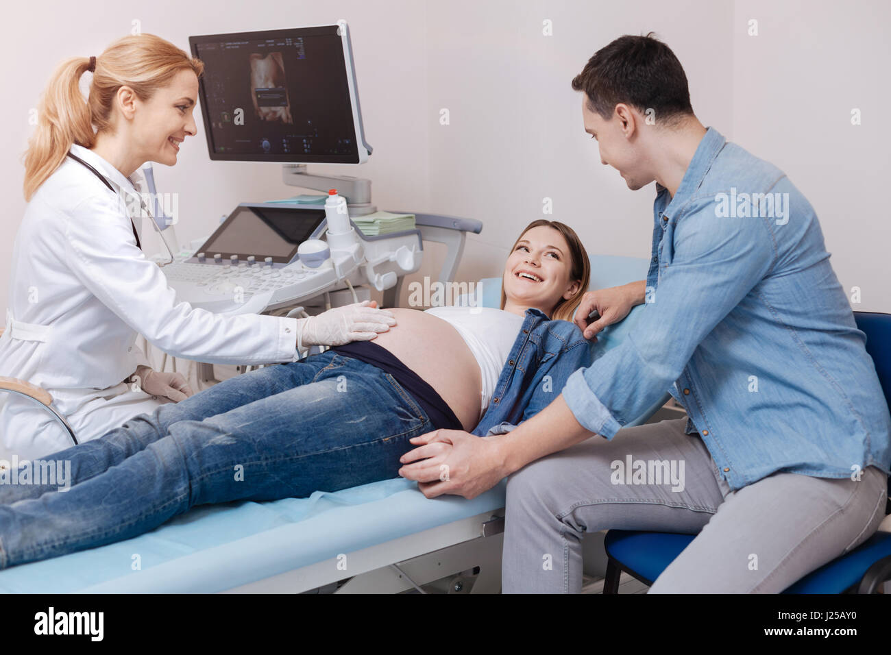 Friendly sonographer examining pregnant belly in the clinic Stock Photo ...
