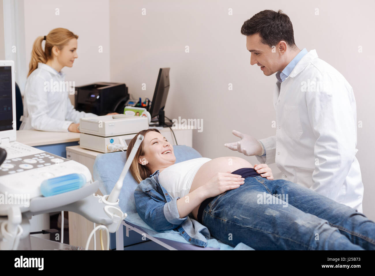 Friendly physicians providing pregnant belly examination in the ...