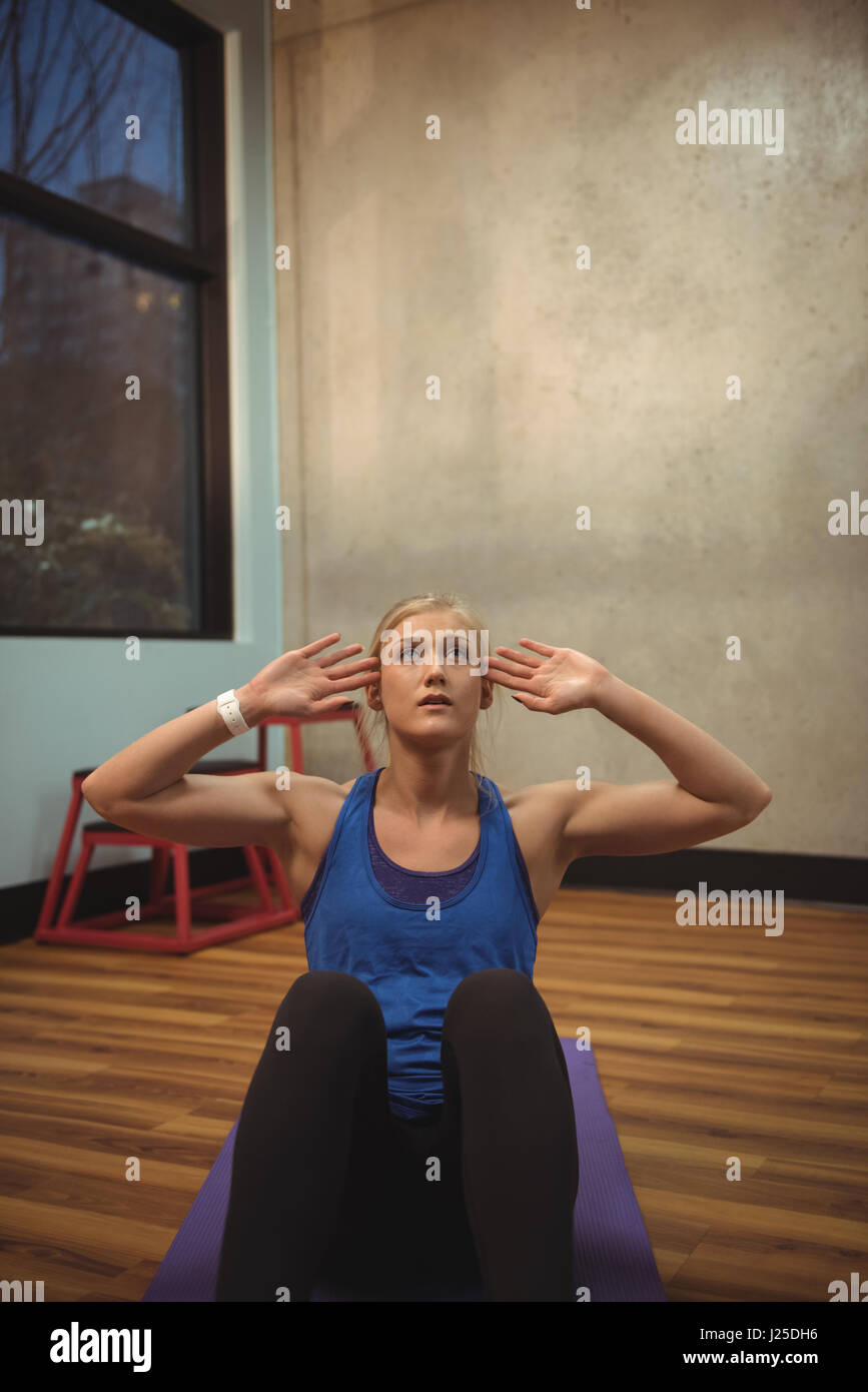 Fit woman performing crunches on a gymnastic mat in the gym Stock Photo ...