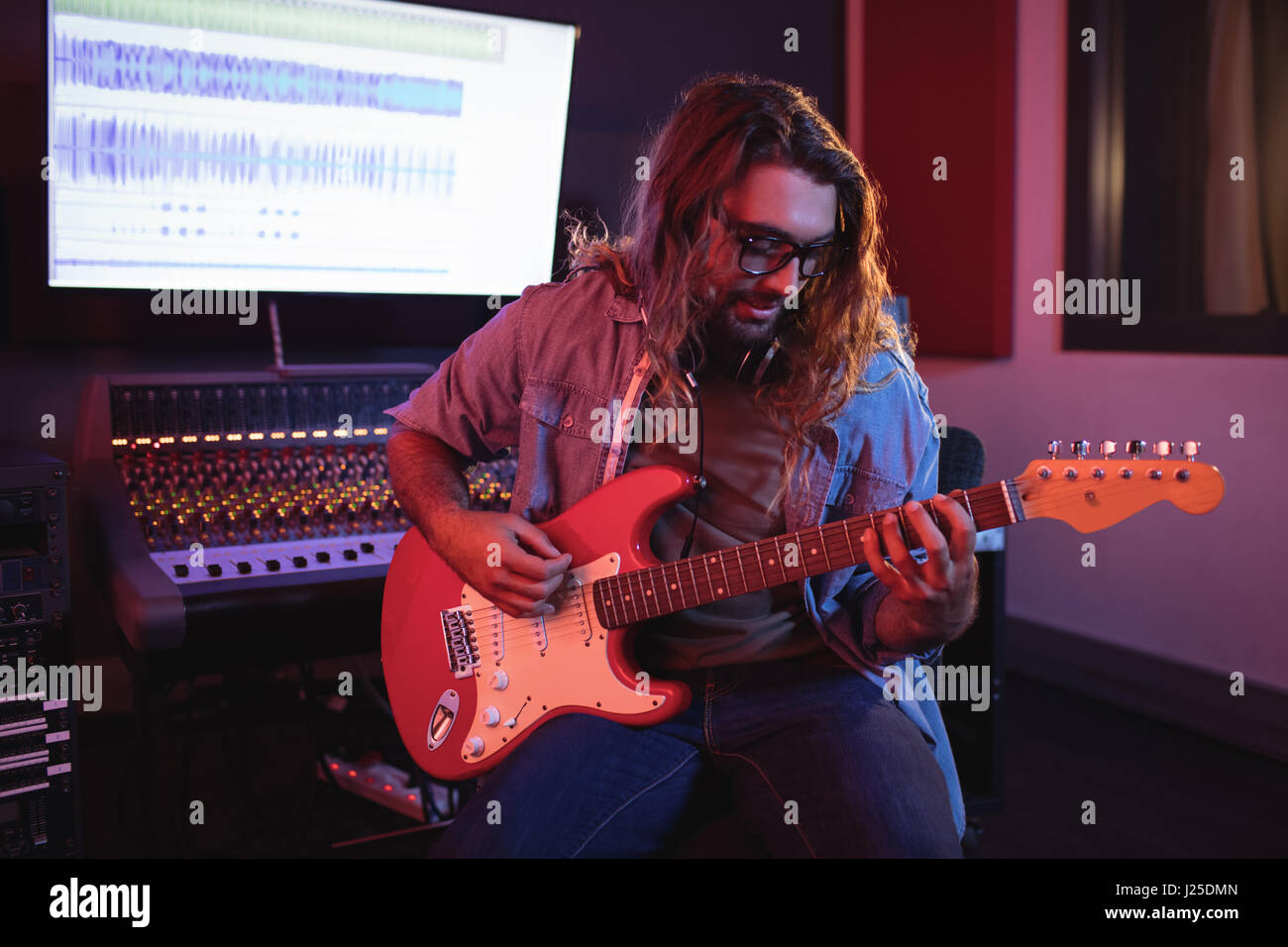 Male audio engineer playing electric guitar in recording studio Stock ...