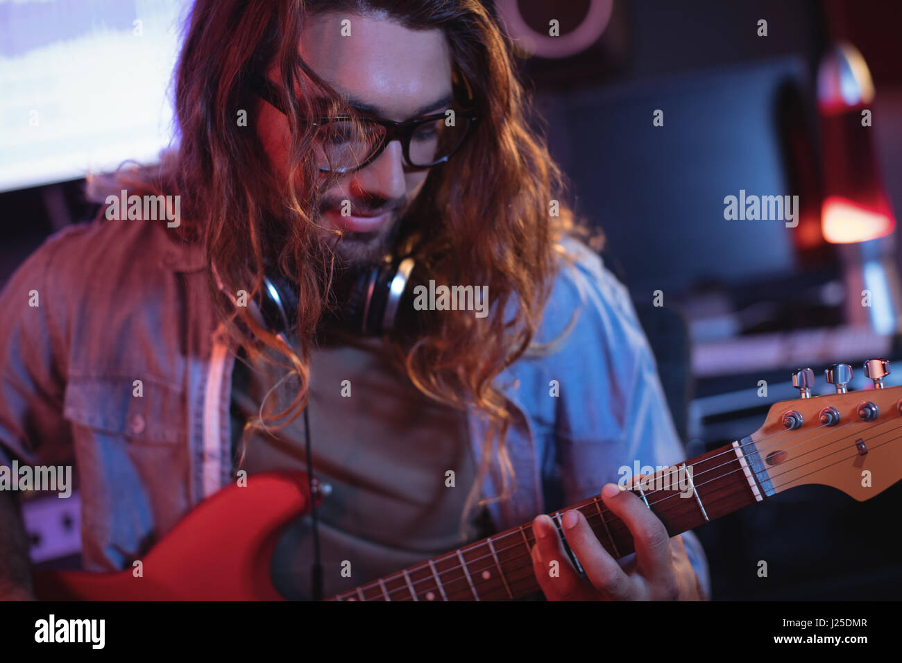 Close-up of male audio engineer playing electric guitar in electric ...