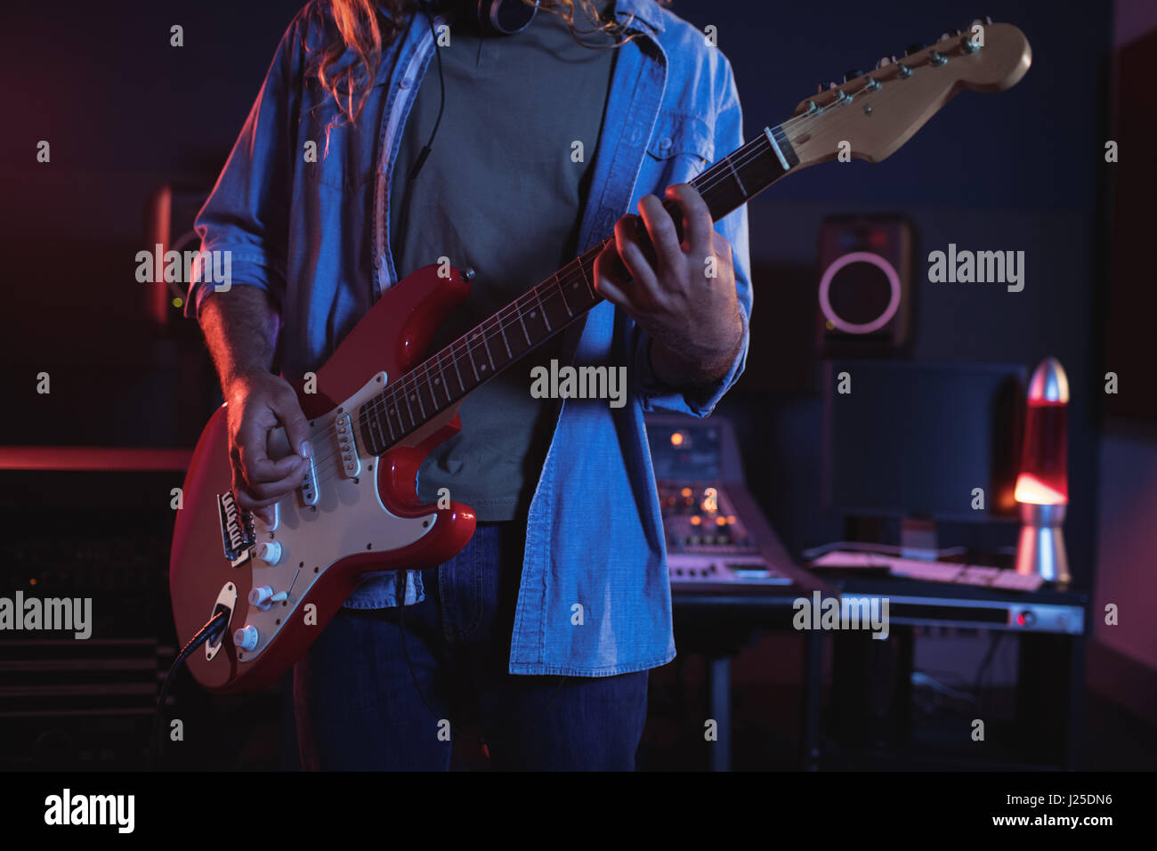 Mid section of audio engineer playing electric keyboard in recording ...