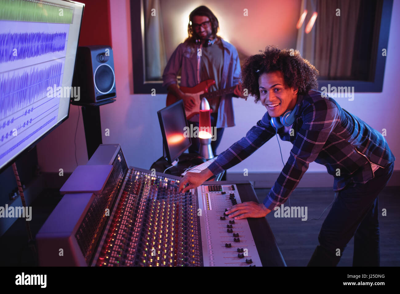 Portrait of male audio engineers using sound mixer in recording studio ...