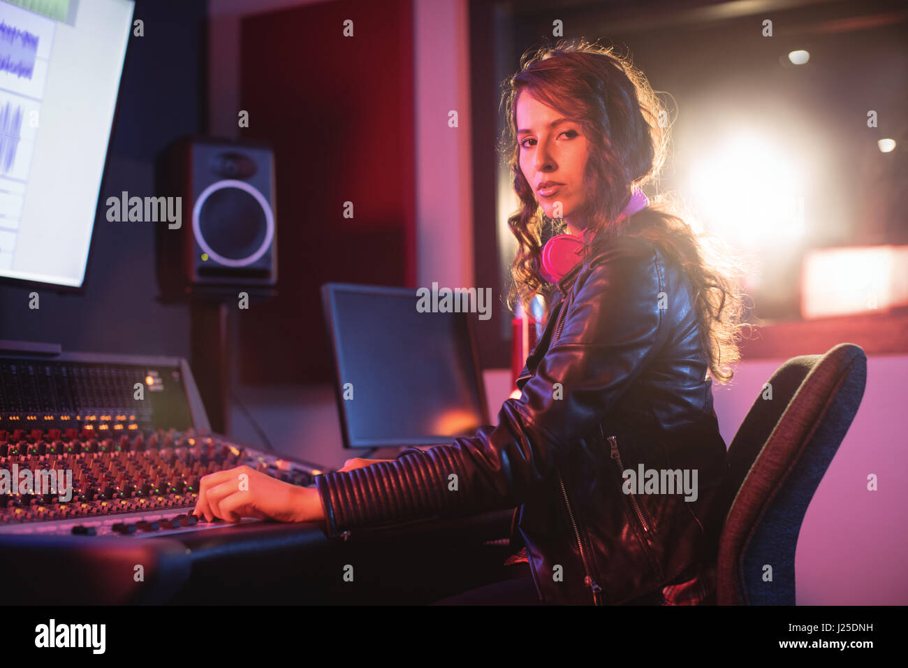 Portrait of female audio engineer using sound mixer in recording studio ...