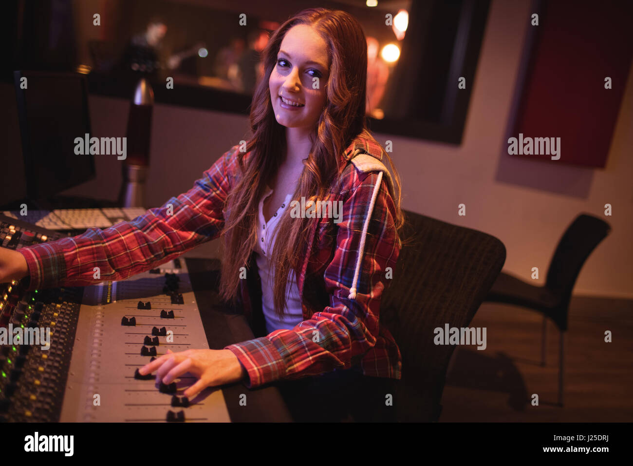 Portrait of female audio engineer using sound mixer in recording studio ...
