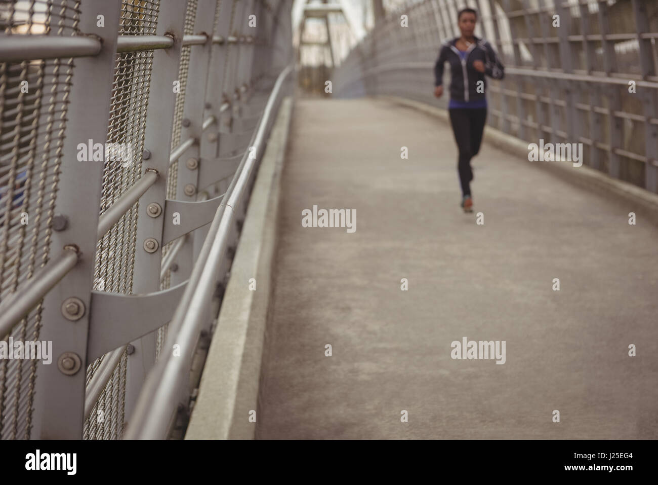 Full length of young woman running on bridge Stock Photo - Alamy