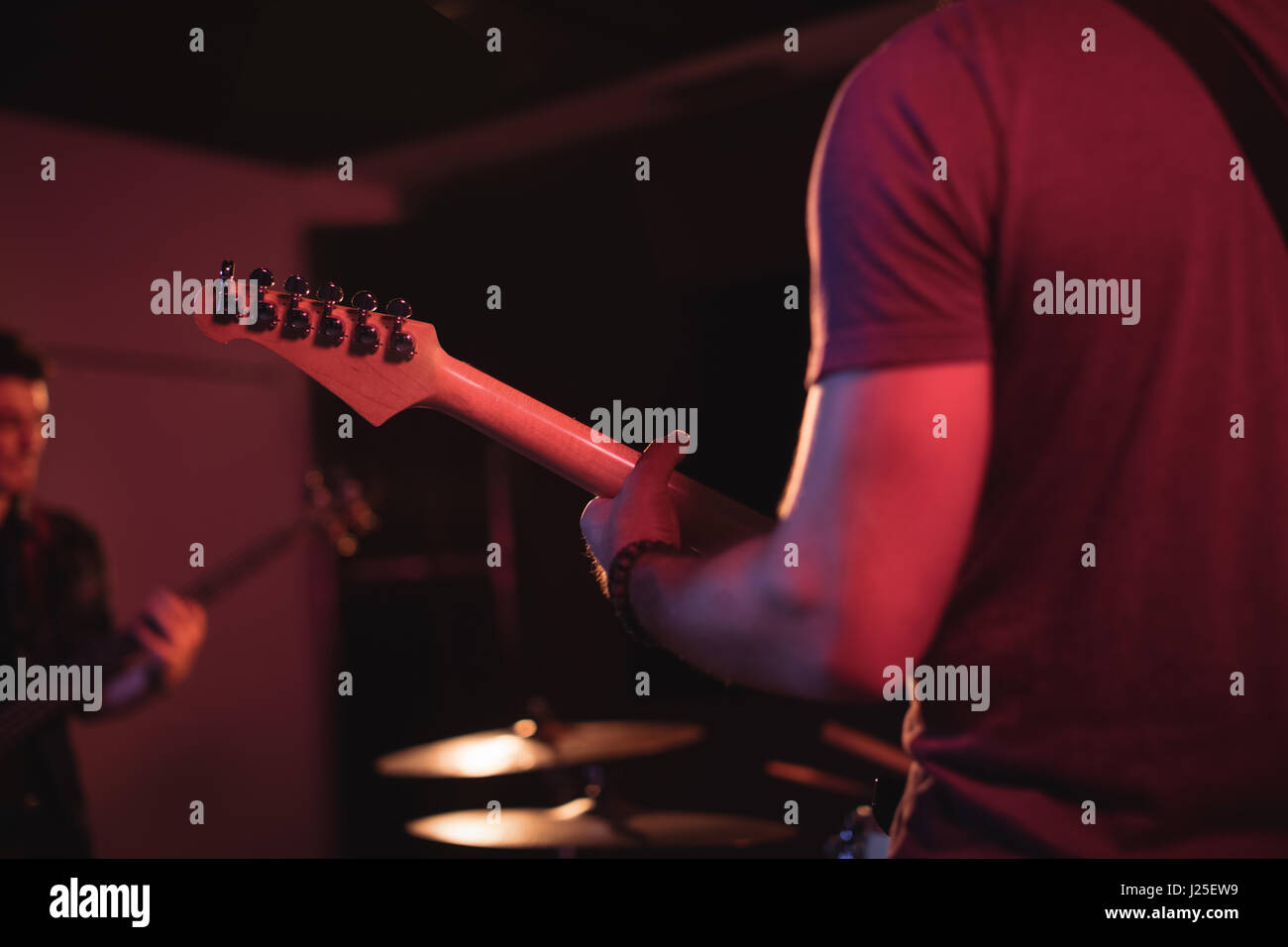 Rear view of guitarist playing electric guitar in recording studio ...