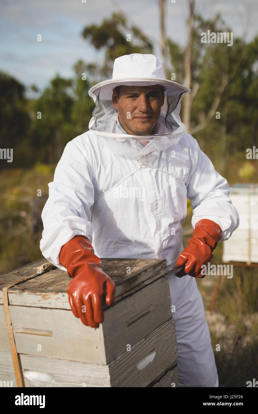 Portrait of confident male beekeeper working on beehive at apiary Stock ...