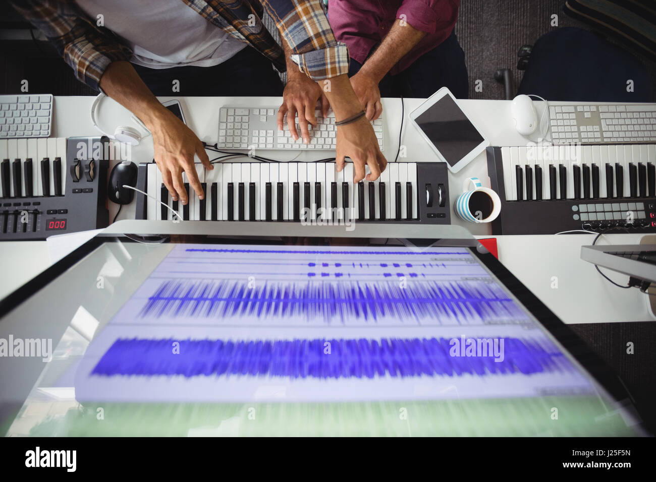 Mid-section of two sound engineers working together in studio Stock ...