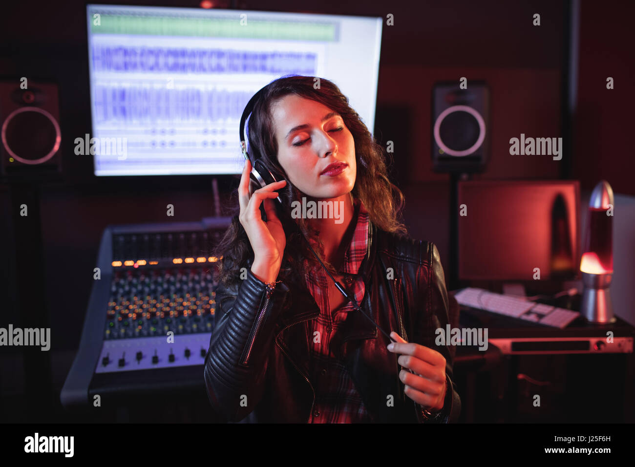 Female audio engineer listening music on headphones in recording studio ...