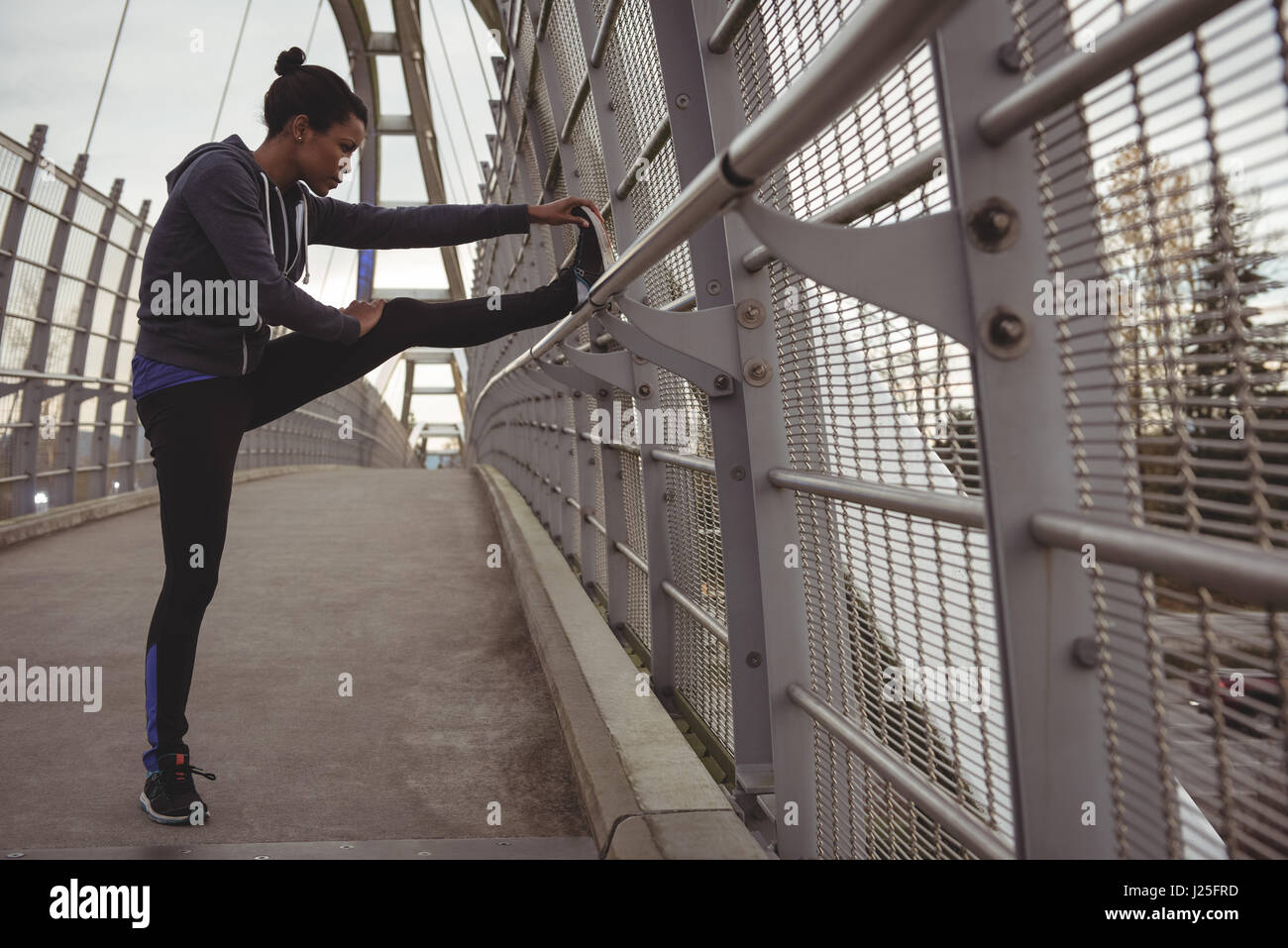 Side view of woman stretching legs on railing at bridge Stock Photo - Alamy