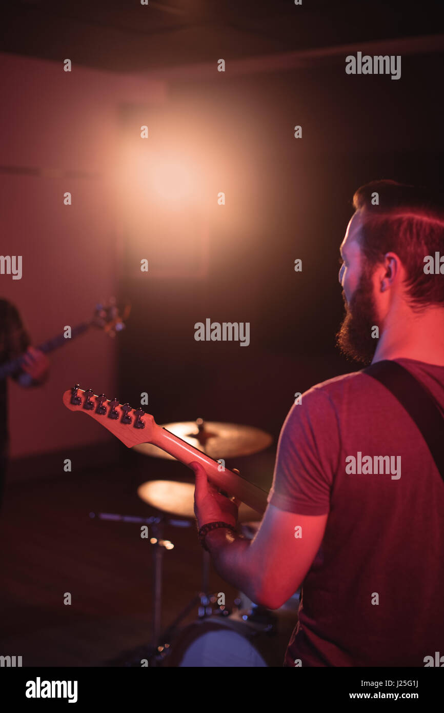 Rear view of guitarist playing electric guitar in recording studio ...