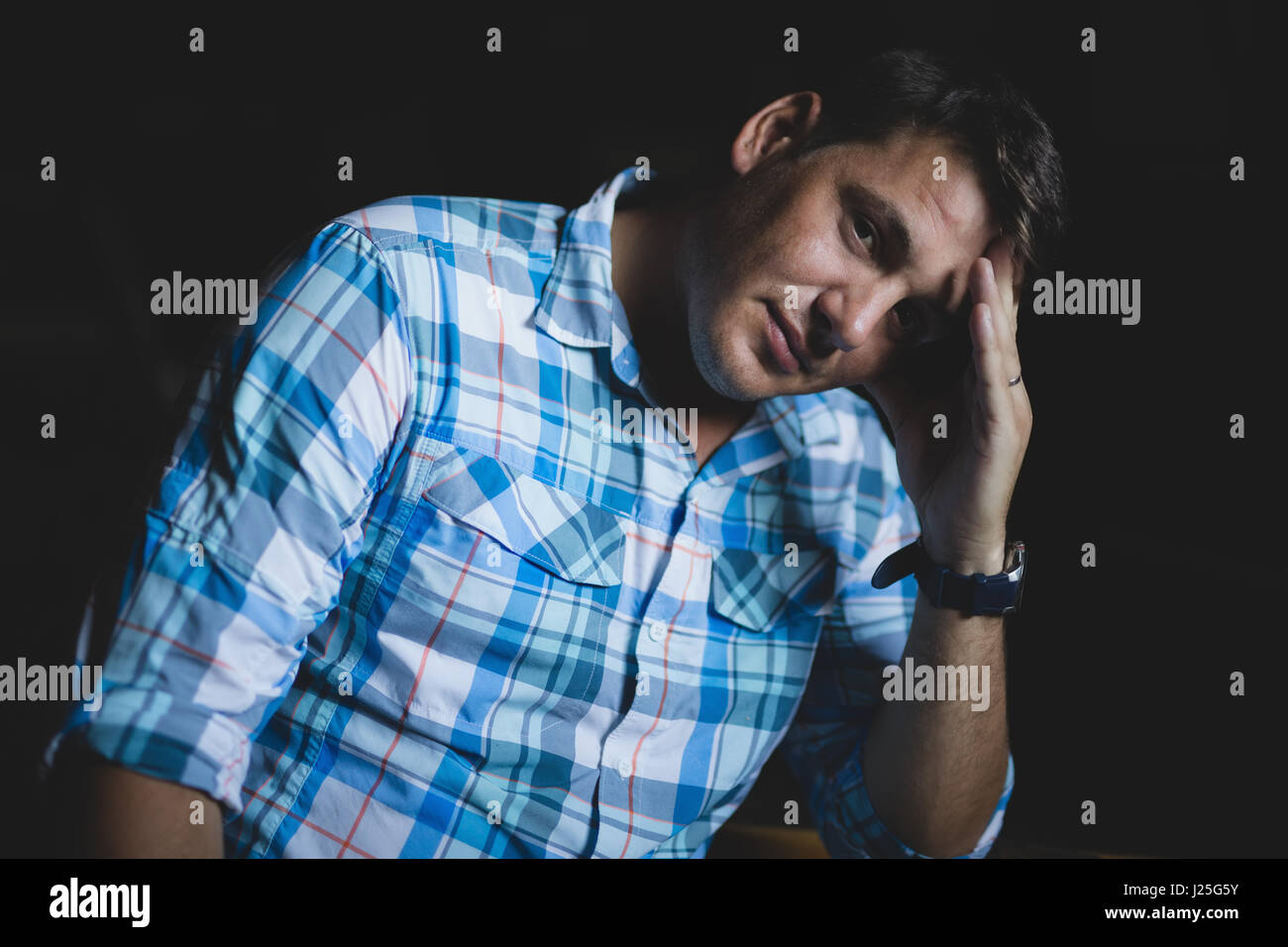 Portrait of man with hand in head against black background Stock Photo ...