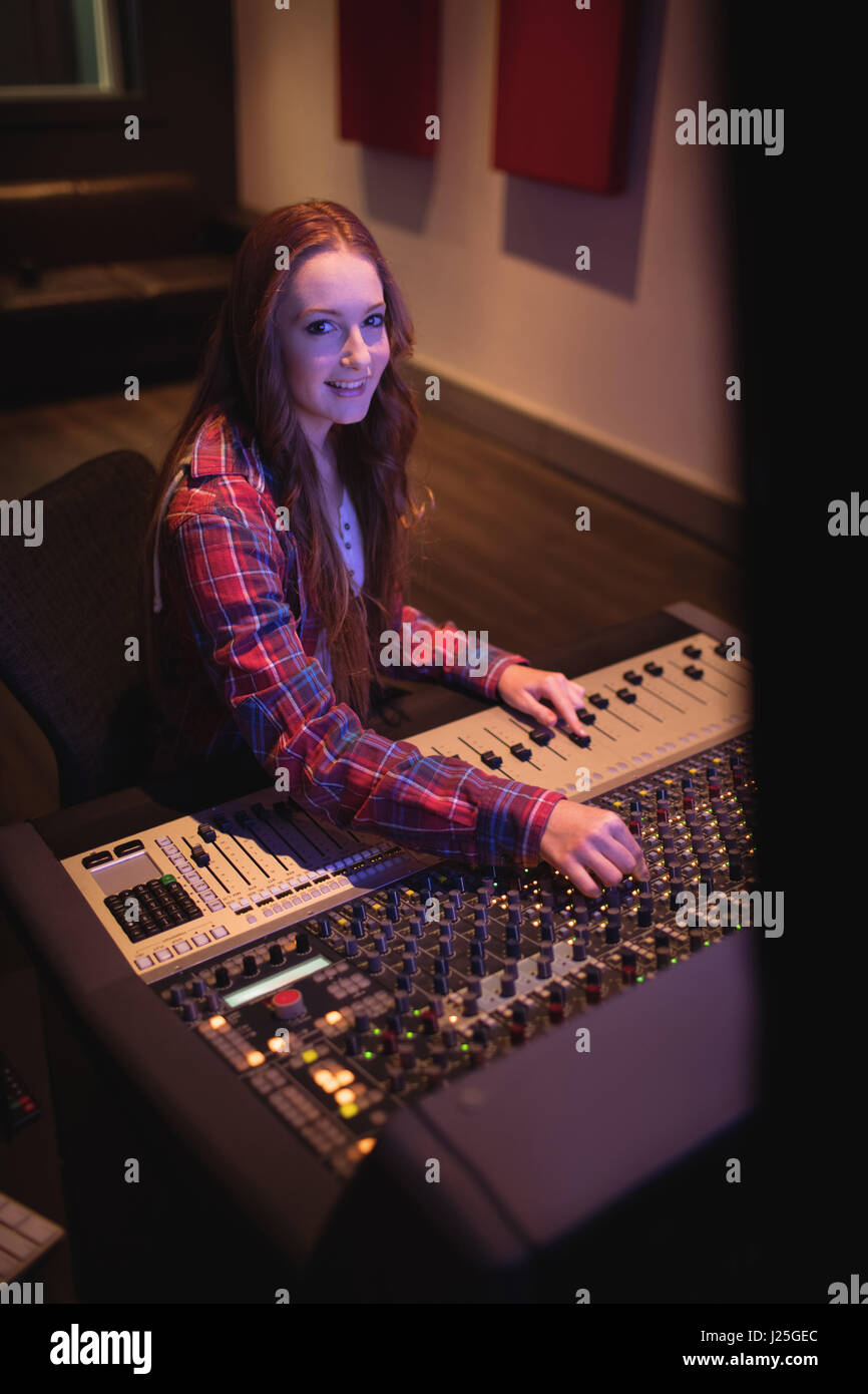 Portrait of female audio engineer using sound mixer in recording studio ...