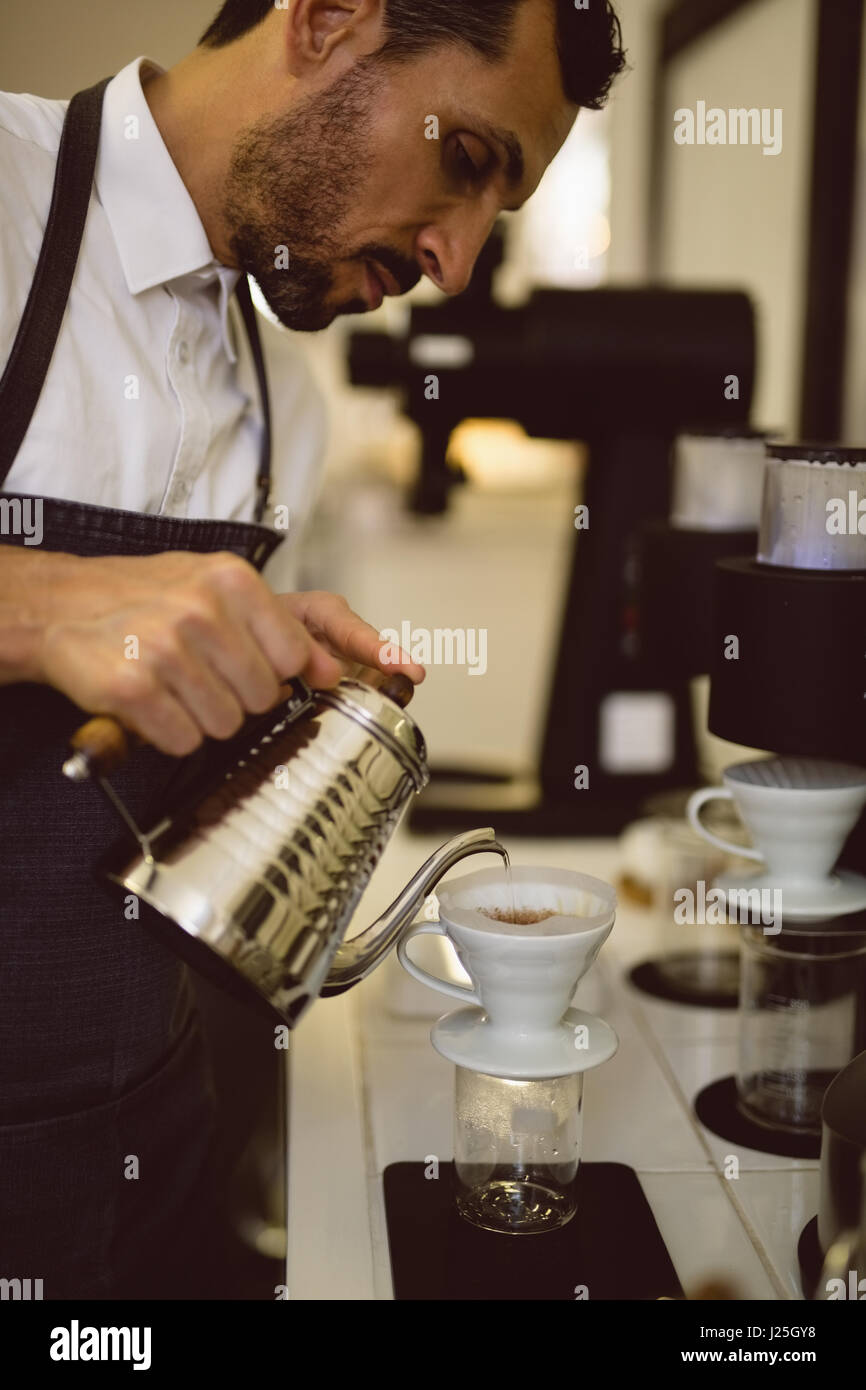 Barista pouring hot water through funnel in coffee shop Stock Photo - Alamy