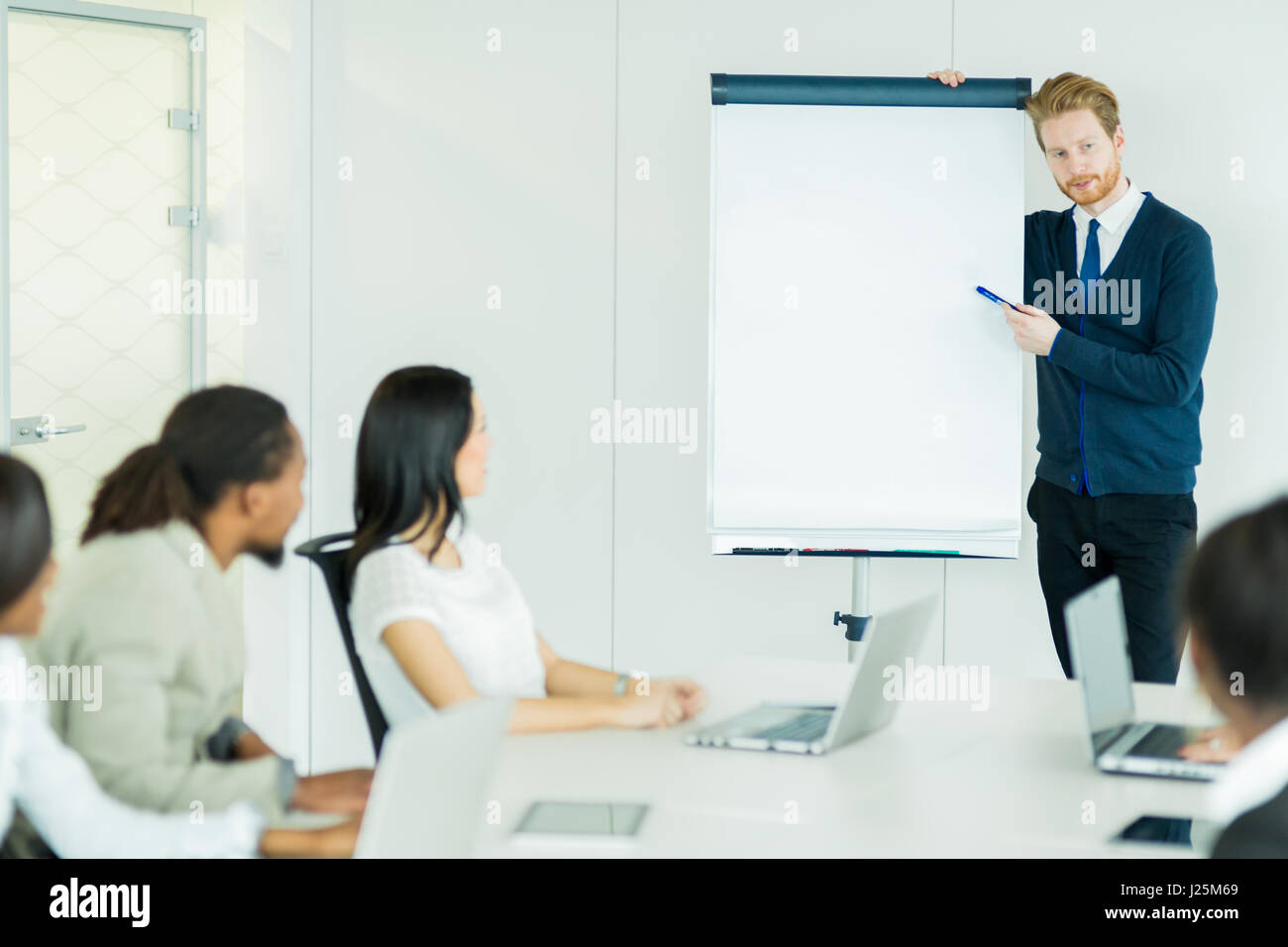 Young business people sitting at a conference table while listening to ...
