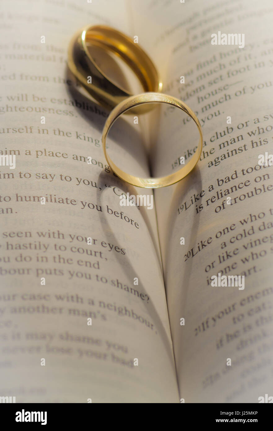 Wedding rings casting a heart shape on a book Stock Photo - Alamy