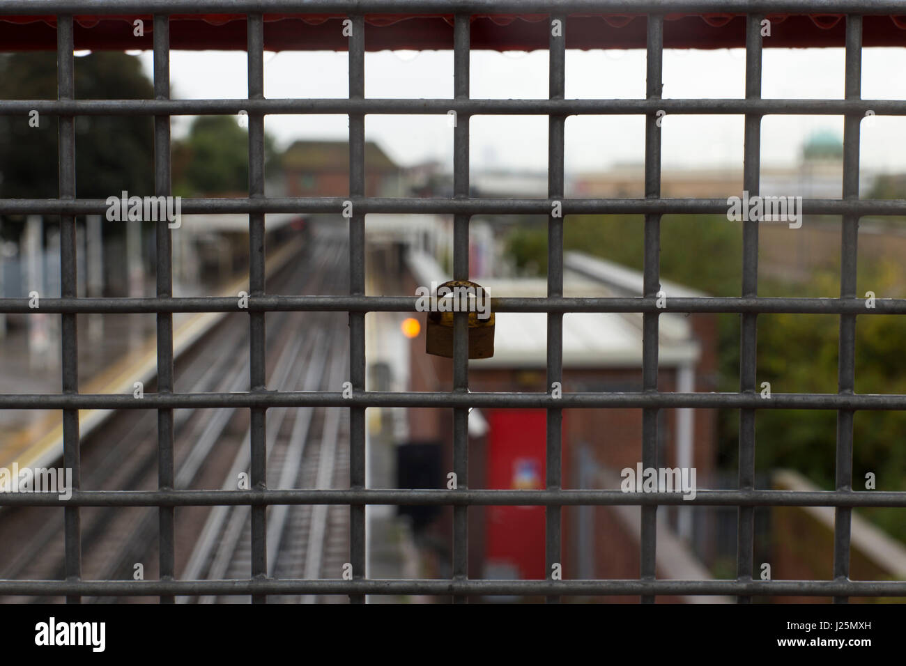 Padlock on grid fence on bridge overlooking Leyton underground station ...