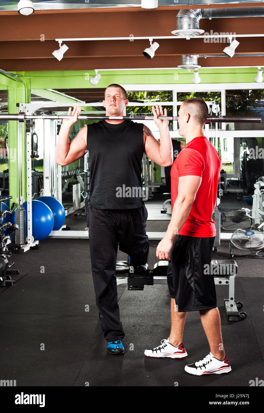 A shot of a male personal trainer assisting a male athlete training ...