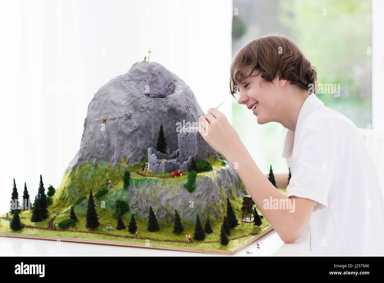 Teenager working on model building school project. Kids build miniature ...