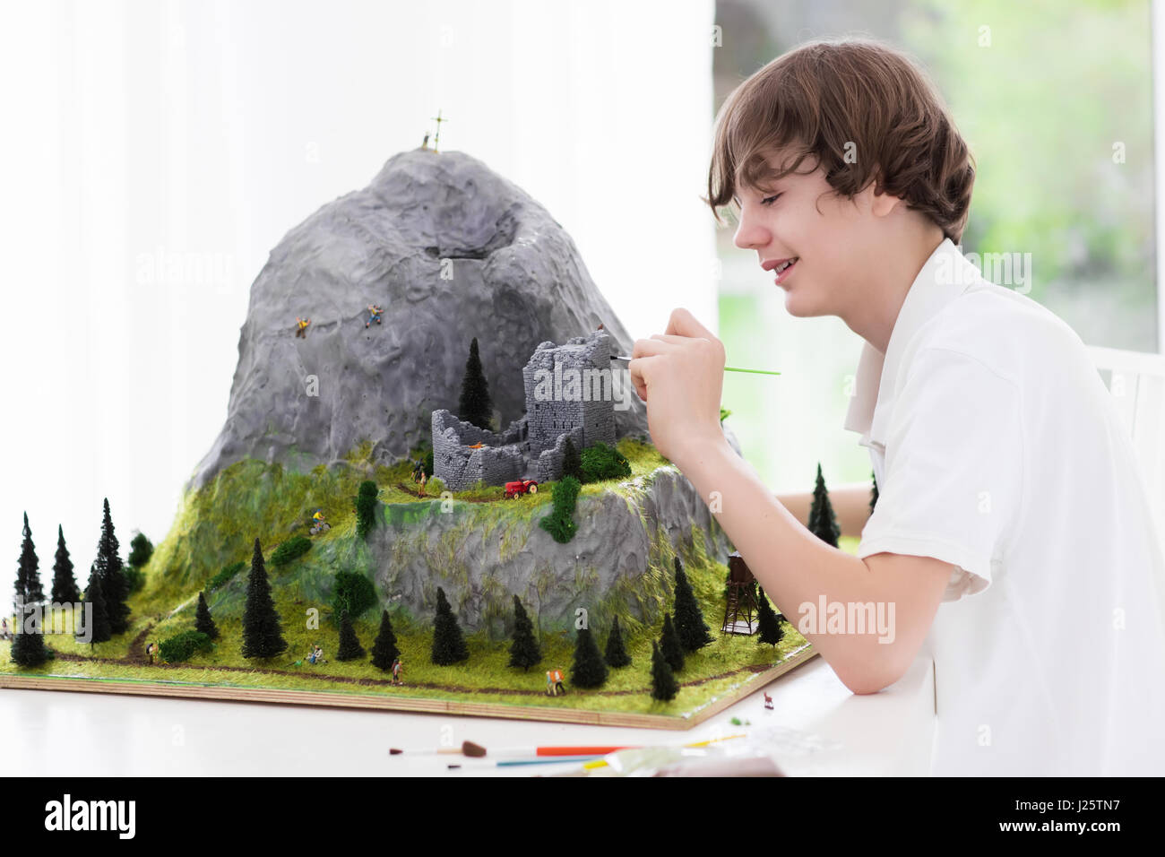 Teenager working on model building school project. Kids build miniature ...
