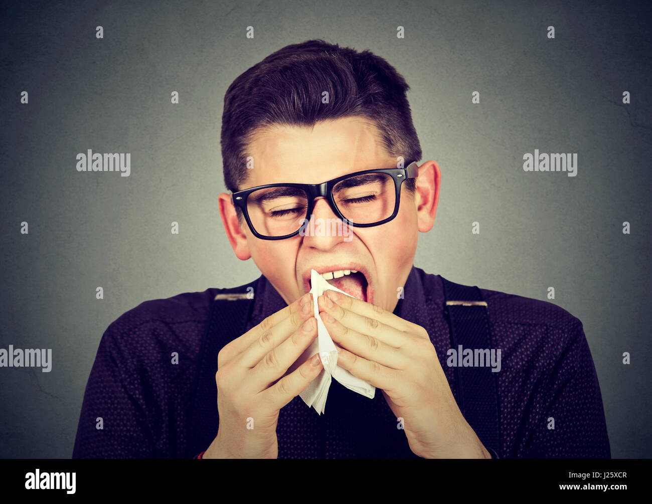 Young man with cold sneezing in tissue Stock Photo - Alamy
