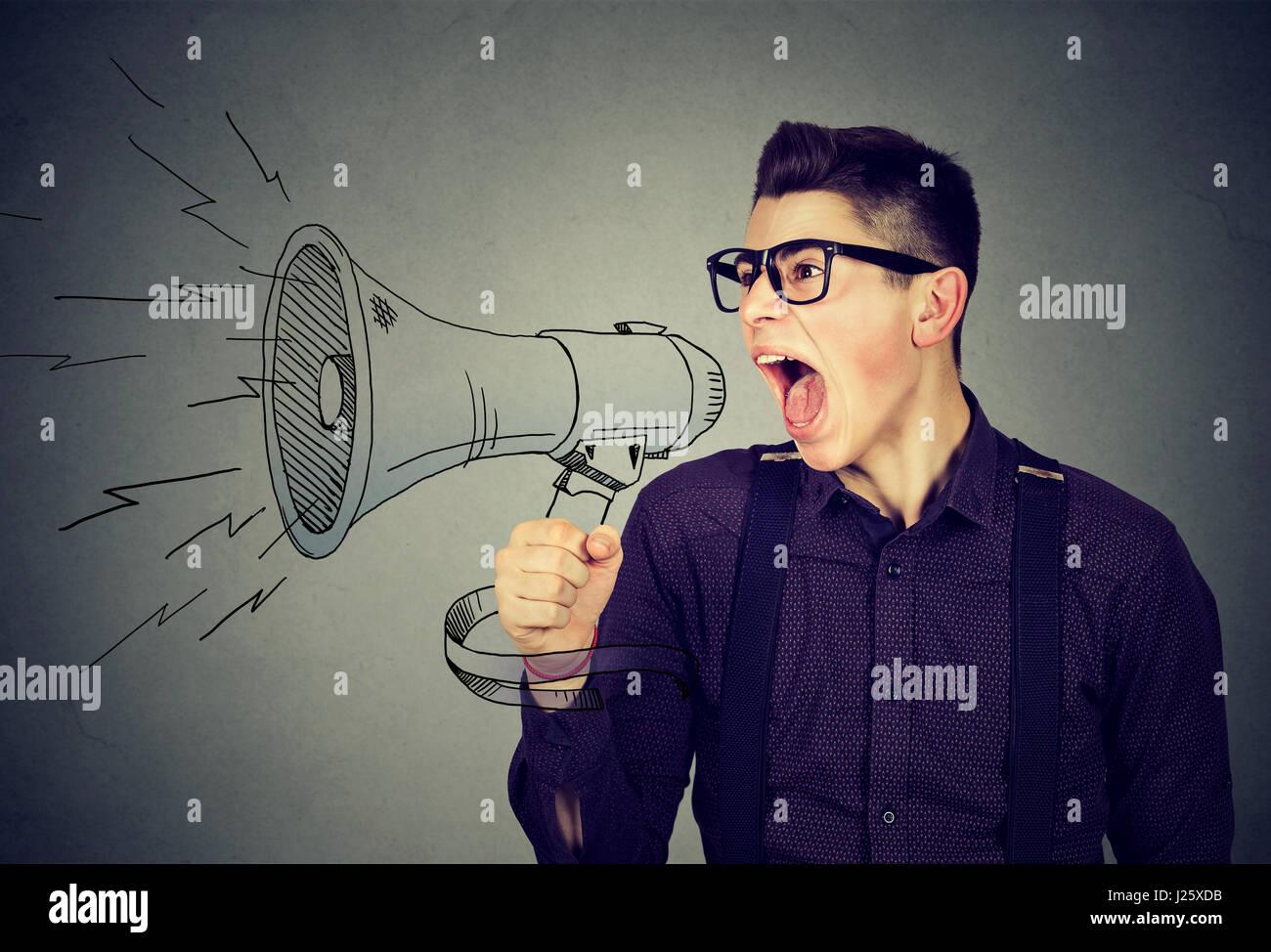 Angry young man screaming in megaphone isolated on gray background ...