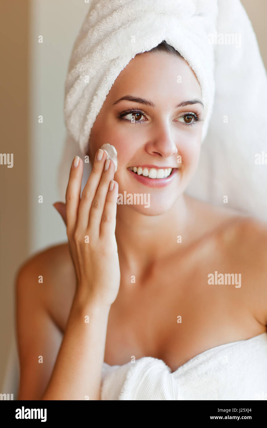 A shot of a young beautiful woman applying lotion to her face Stock ...