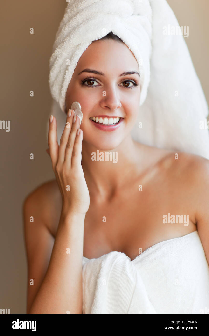 A shot of a young beautiful woman applying lotion to her face Stock ...