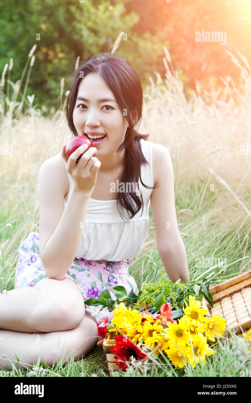 A portrait of a beautiful asian woman eating an apple outdoor Stock ...