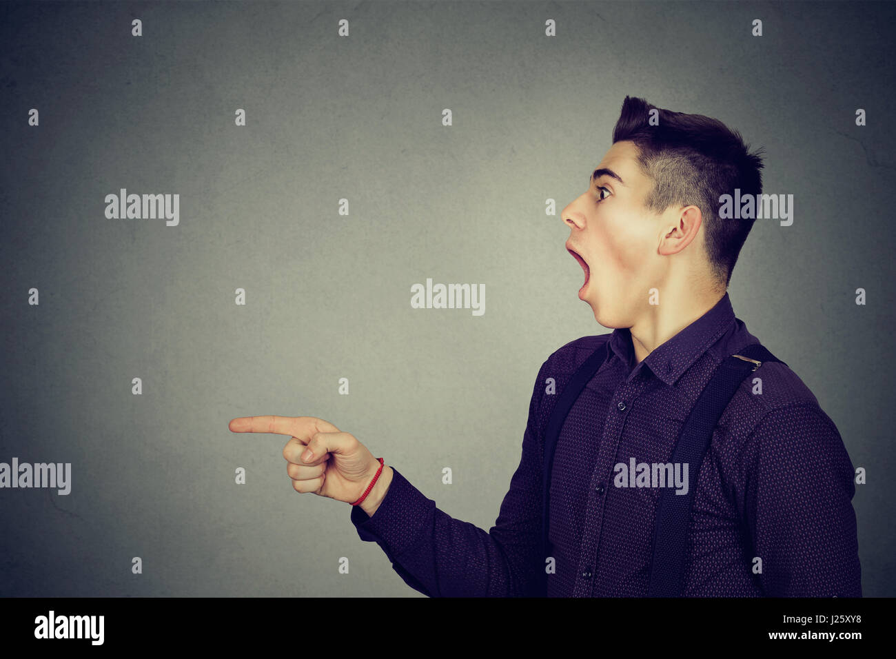 Shocked man pointing finger isolated on gray background with copy space ...