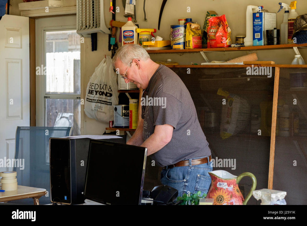A senior Caucasian man shows attention to a desktop computer at a ...