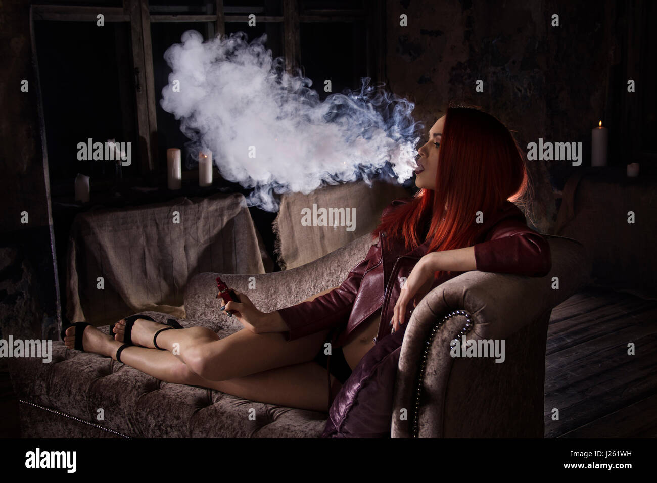 portrait of sexy redhead woman on the sofa vaping e-cigarette , vape mod concept Stock Photo - Alamy