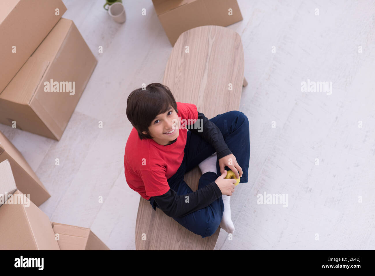 happy little boy sitting on the table with cardboard boxes around him ...