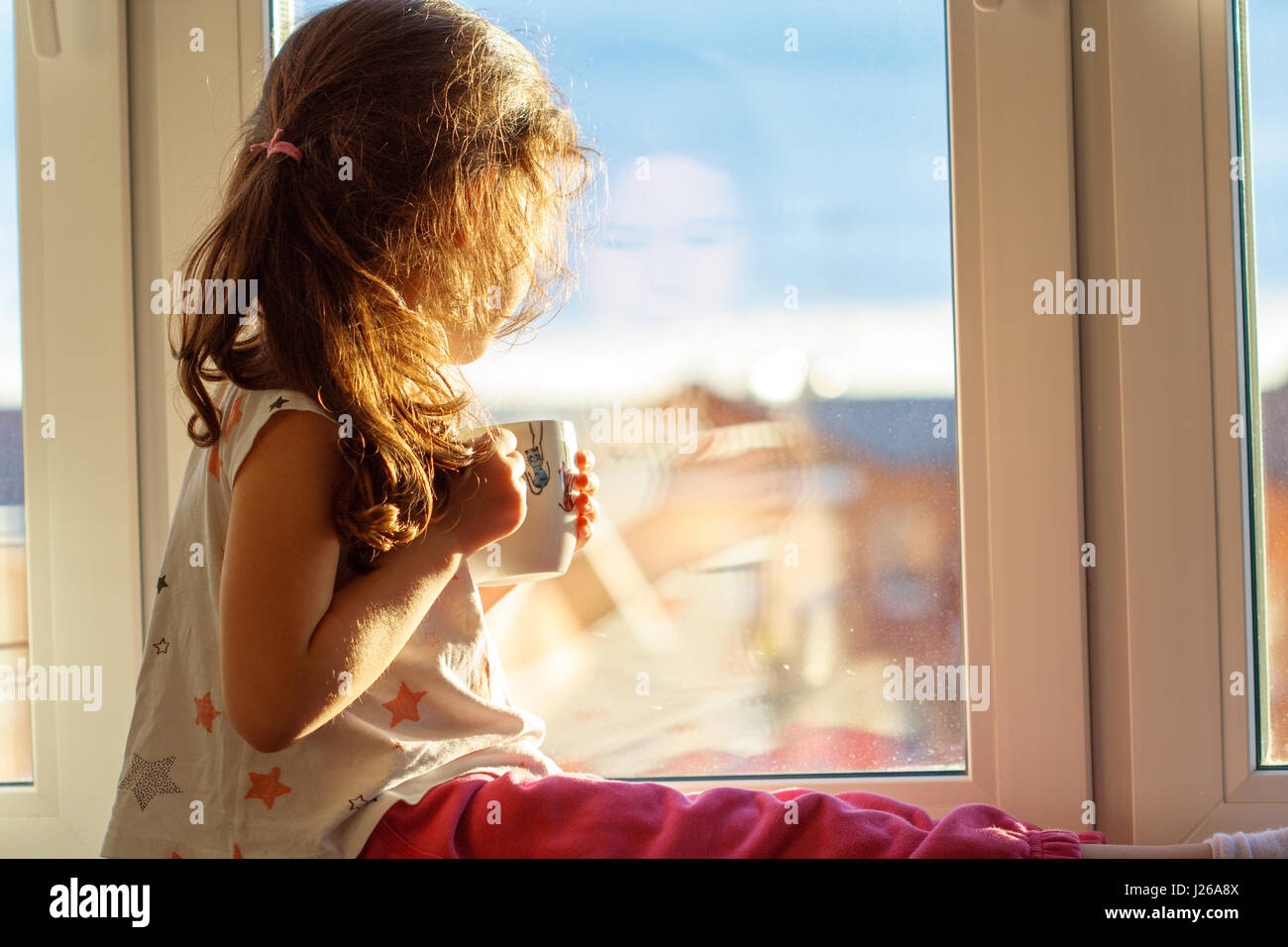 The girl drinks tea from a cup and looks out the window Stock Photo - Alamy