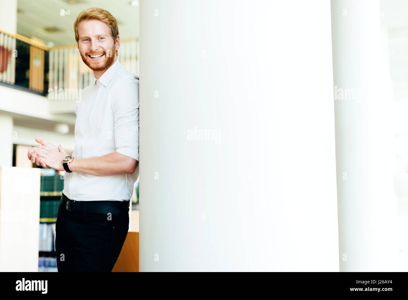 Handsome intelligent male student smiling in library Stock Photo - Alamy