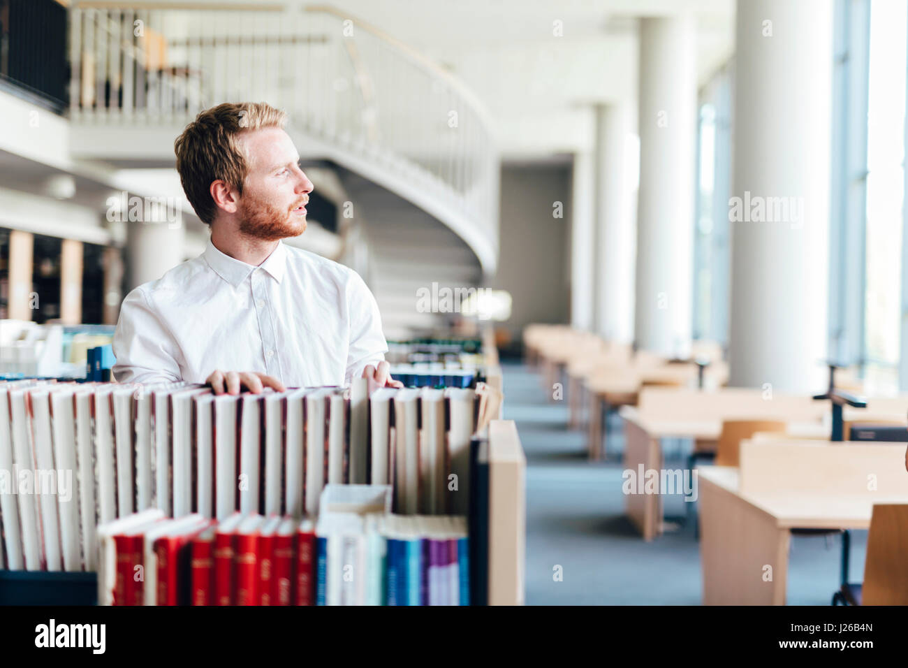 Handsome student searching for a book in a beautiful library Stock ...