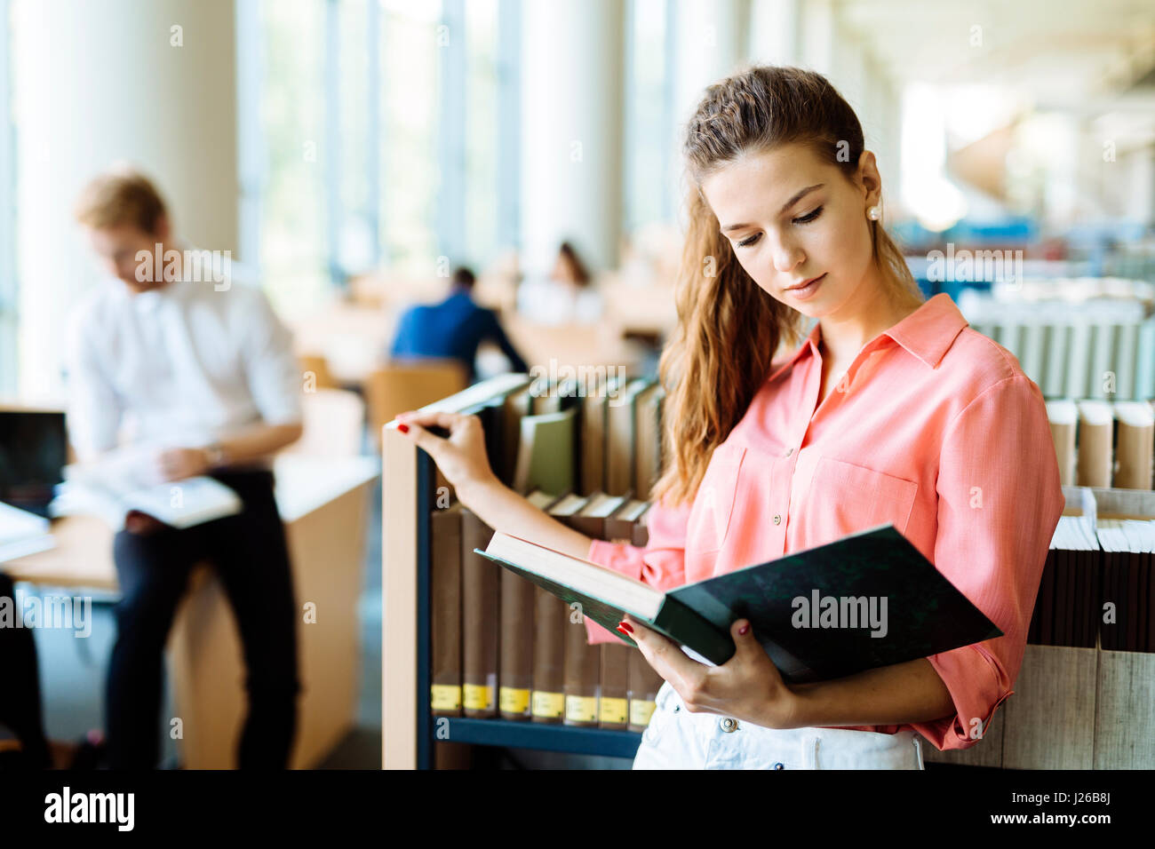 Beautiful woman reading a book in a library and thinking Stock Photo ...