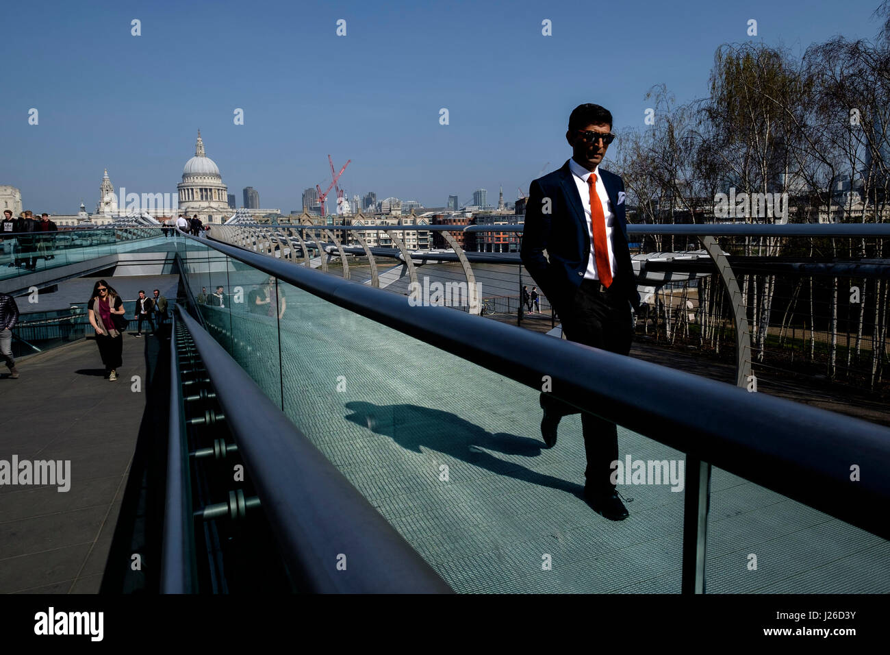 Man wearing suit crossing the Millennium Bridge with St. Paul's ...
