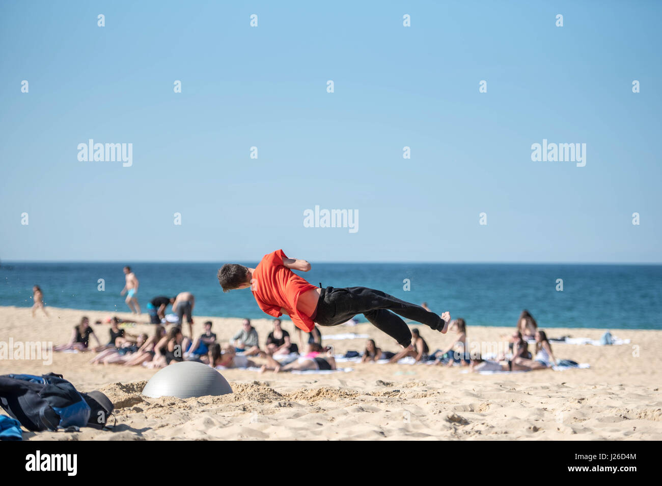 Kids are jumping very high on a beach and doing flip overs turning in ...