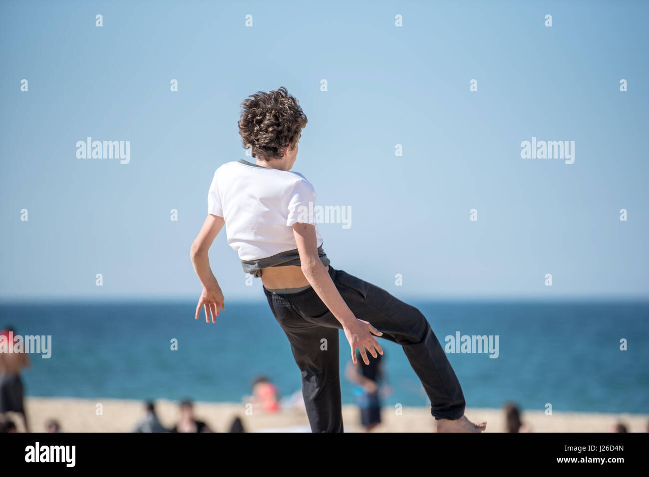 Kids are jumping very high on a beach and doing flip overs turning in ...