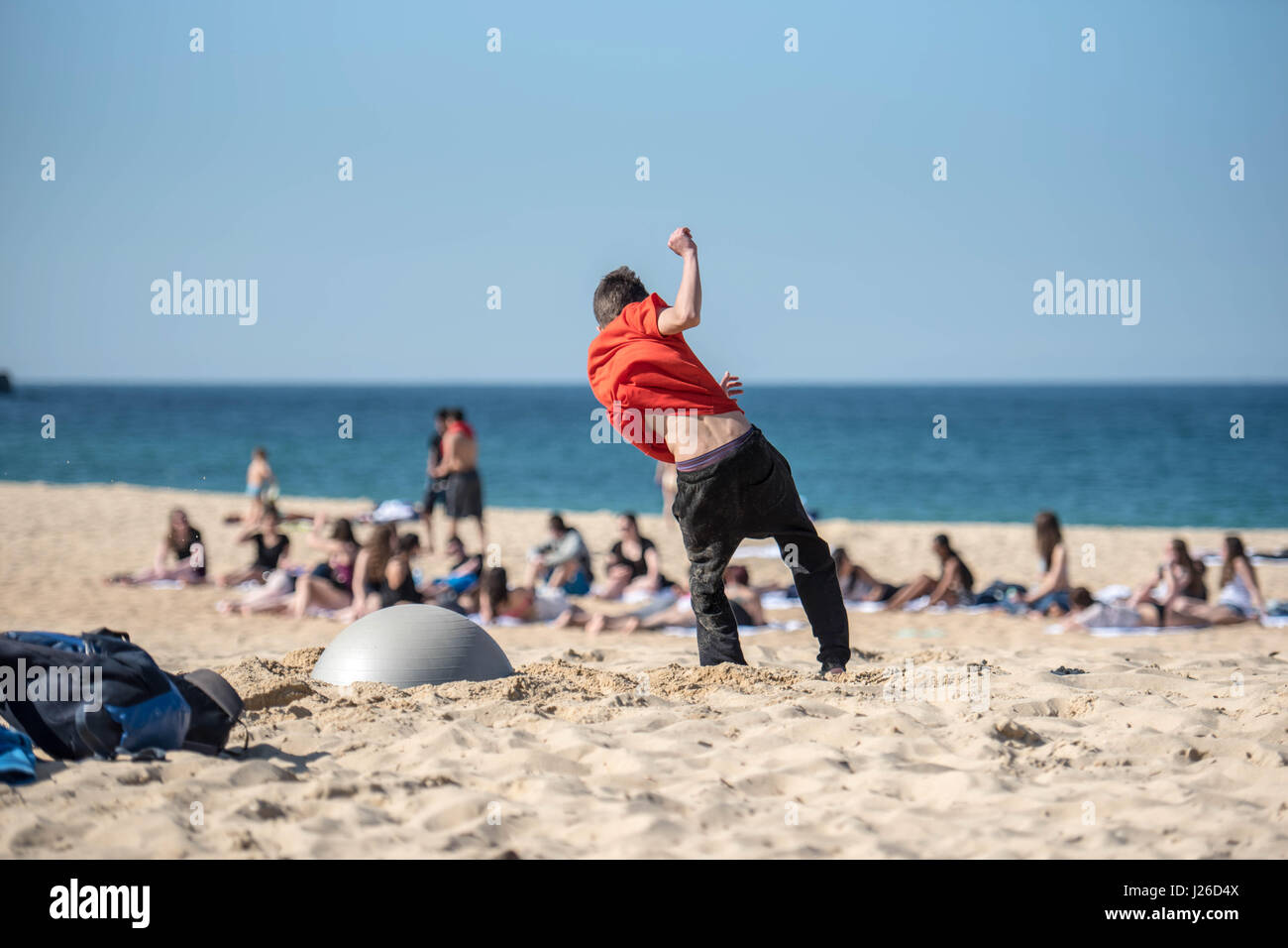 Kids are jumping very high on a beach and doing flip overs turning in ...